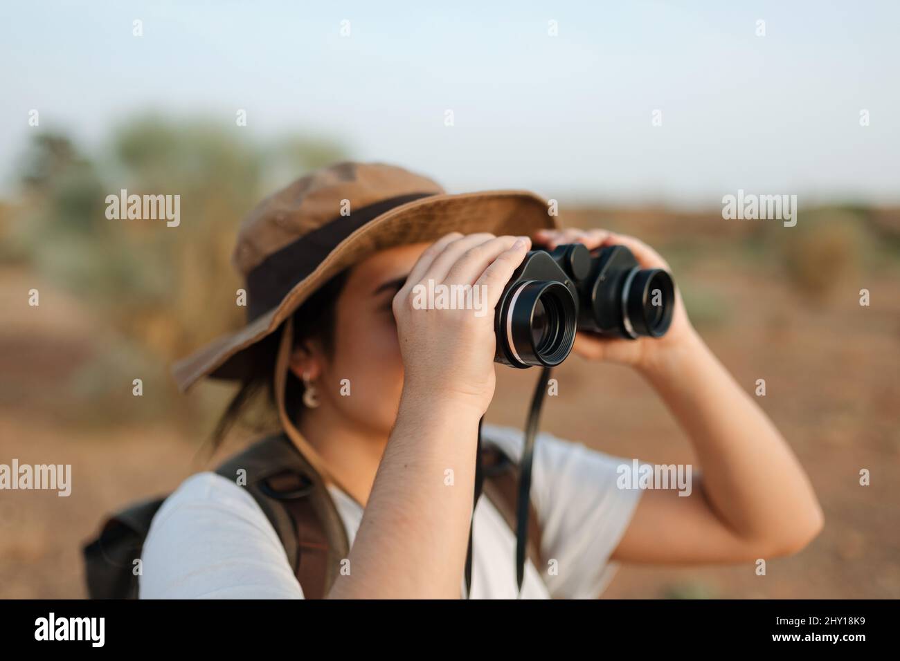 Traveling female with backpack looking through binoculars while ...