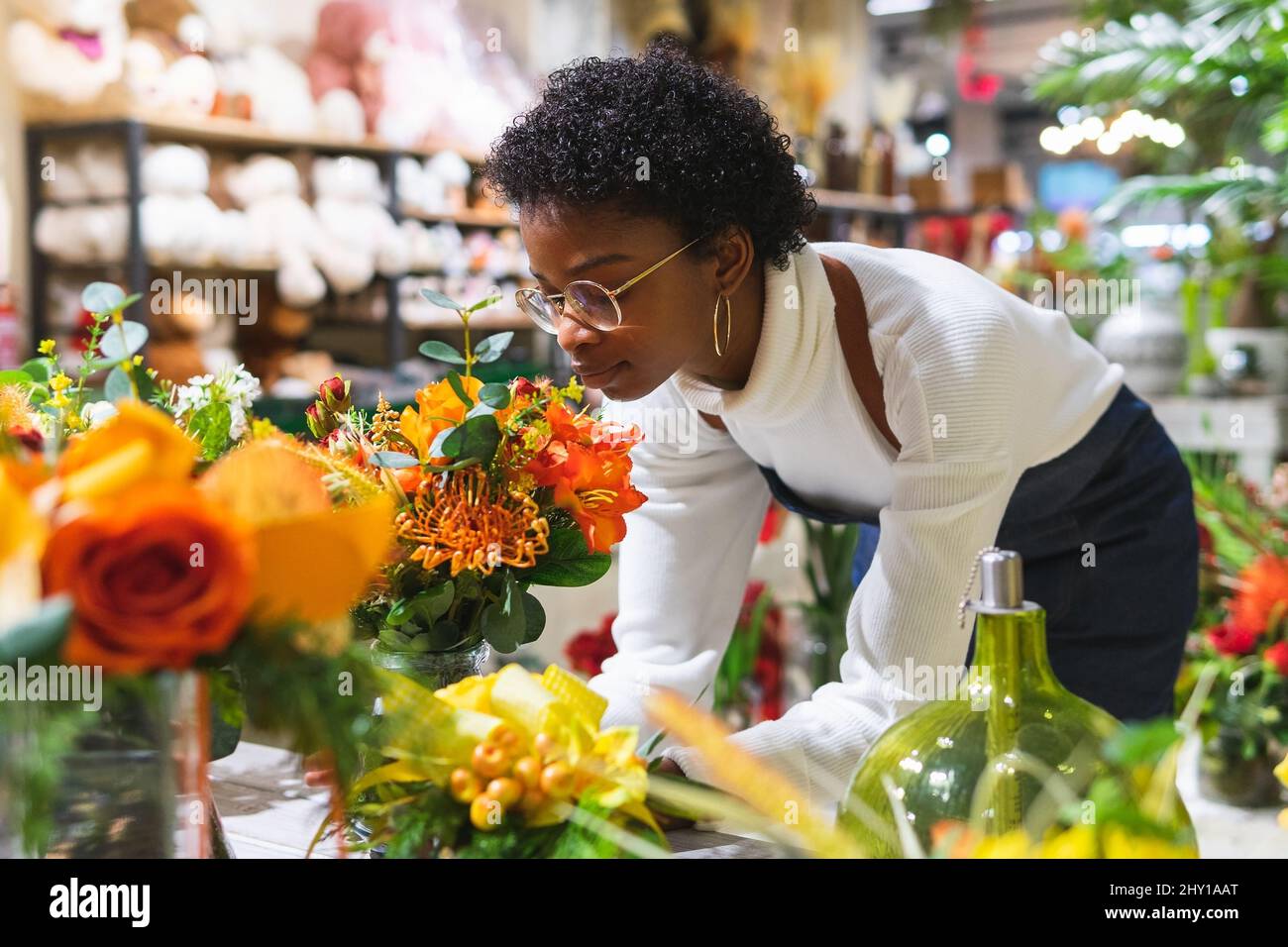 Side view of African American female florist with eyes closed enjoying ...
