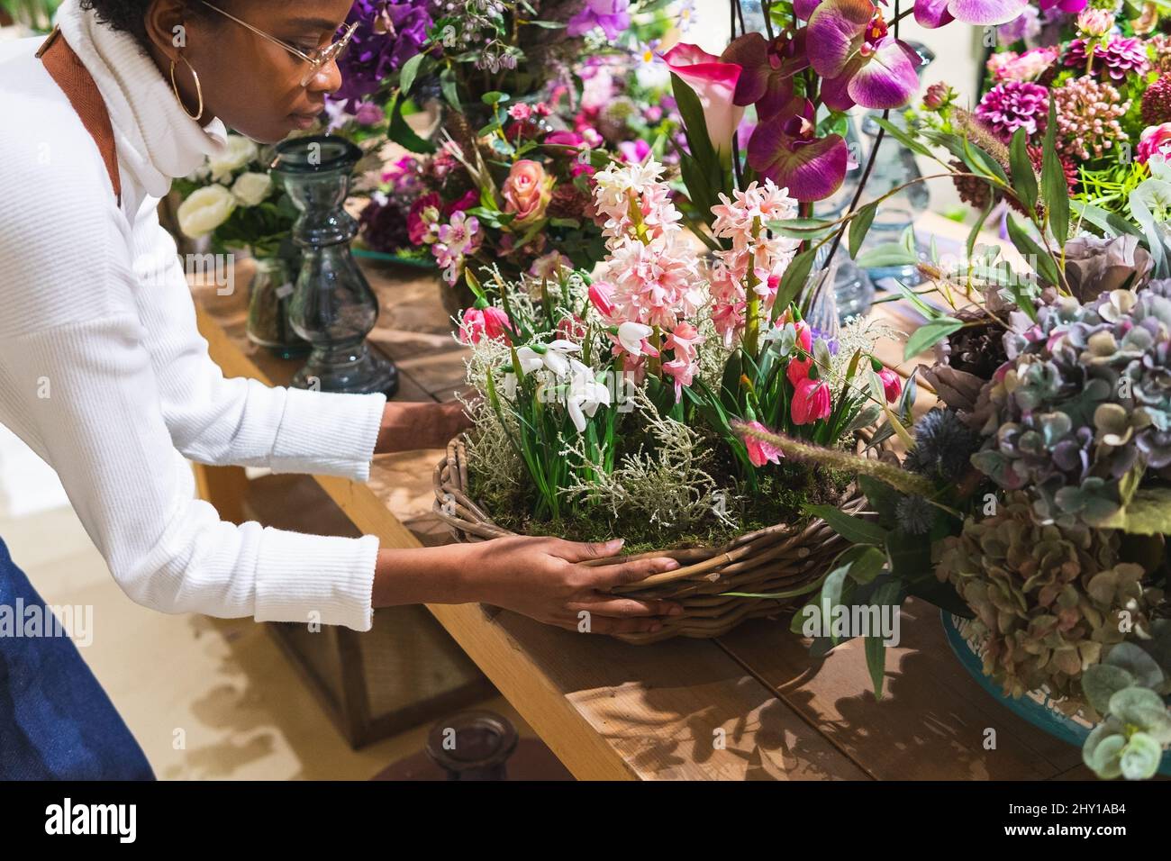 Side view of crop African American female florist putting bouquet of ...
