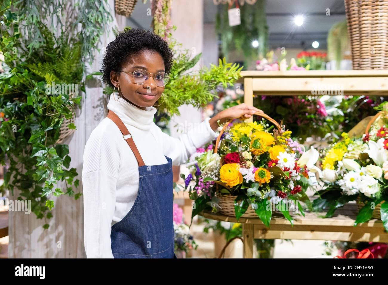 Cheerful African American female florist with bouquet of flowers with ...