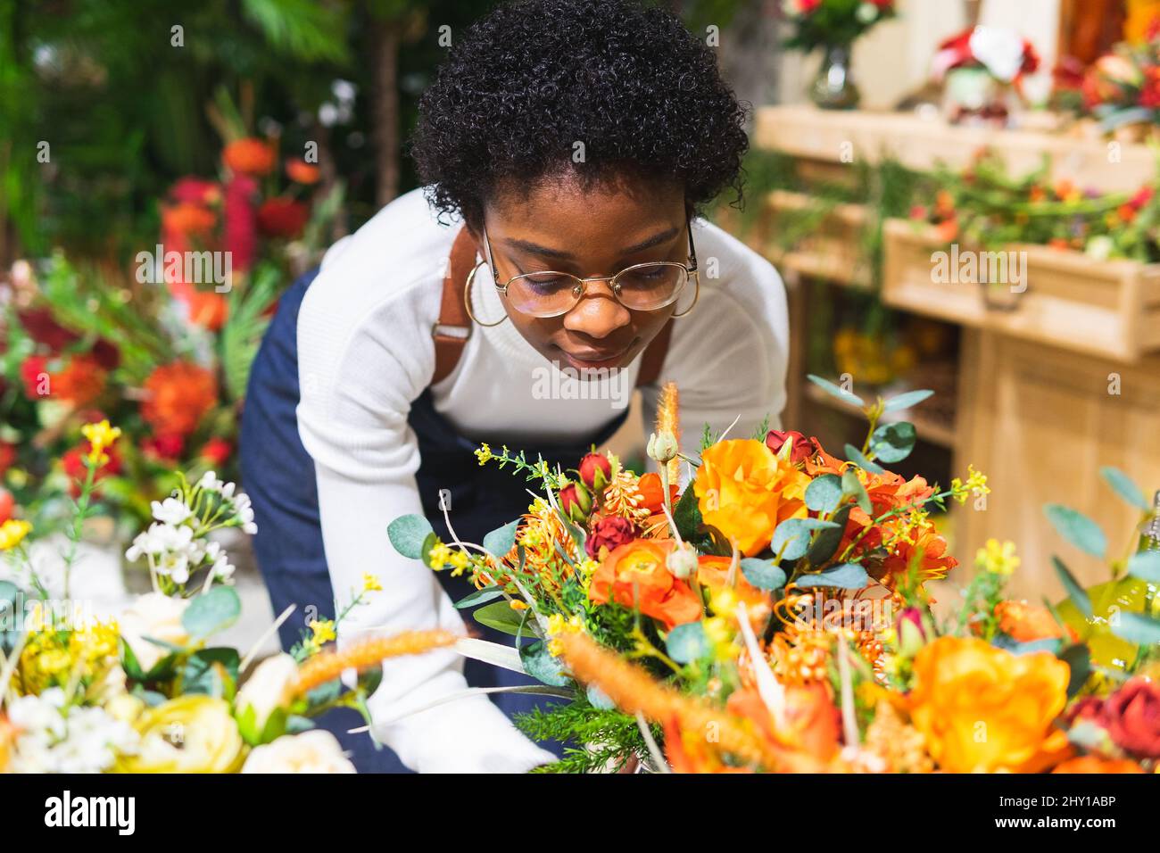 African American female florist with eyes closed enjoying bouquet of ...