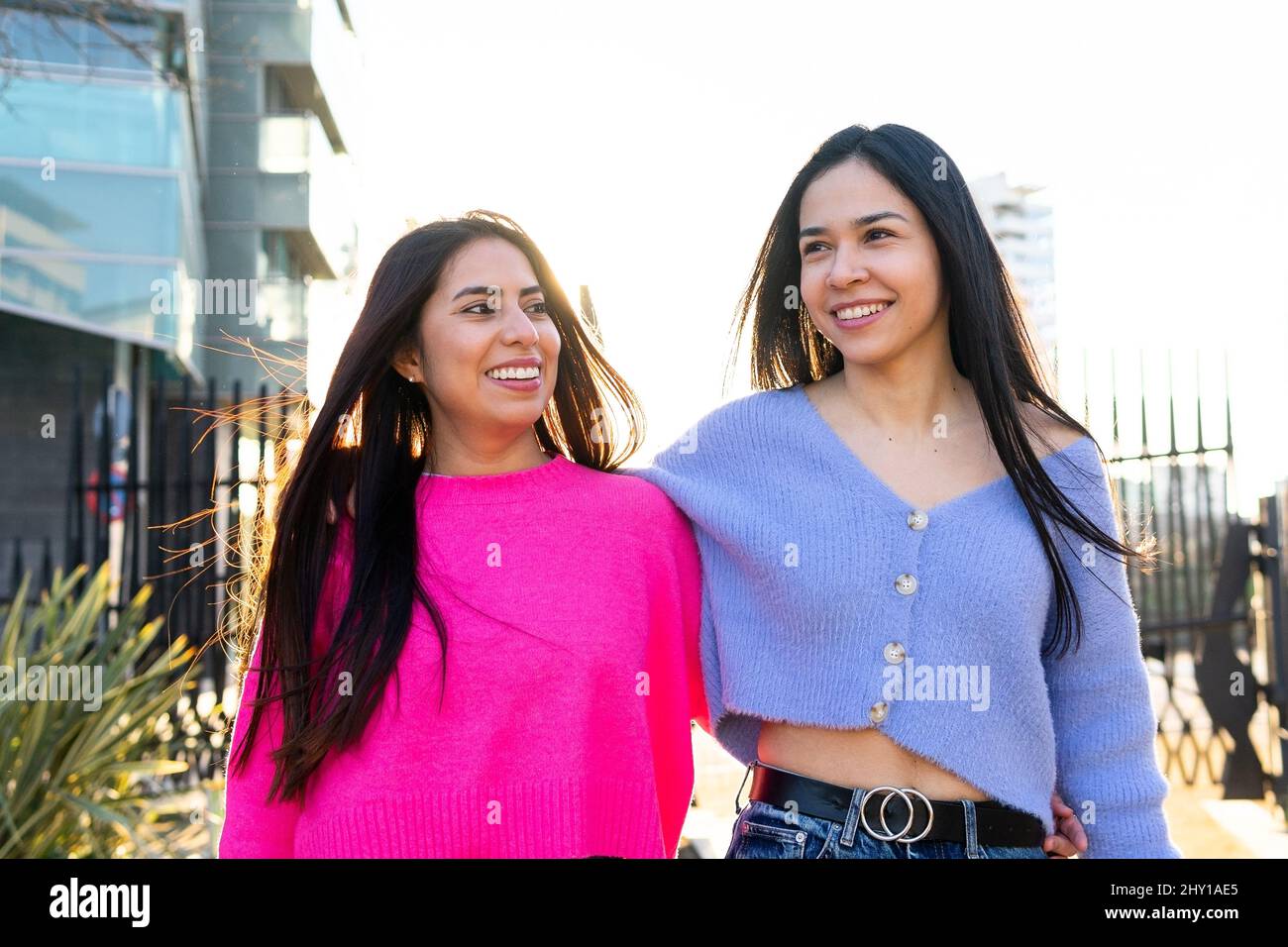 Positive Hispanic female friends with black hair in colorful wear ...
