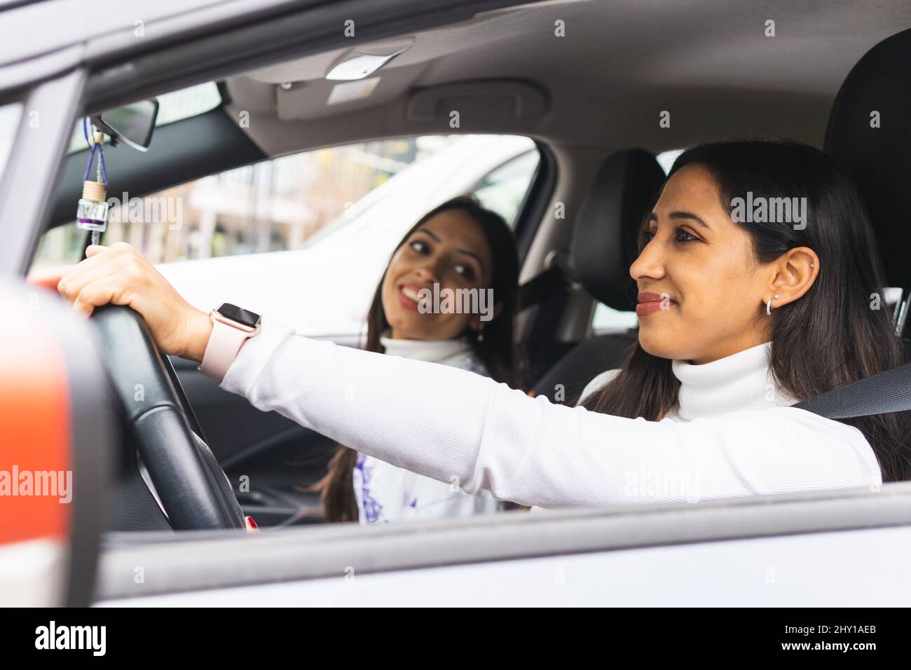 Positive Indian female driver with hand son steering wheel sitting near ...