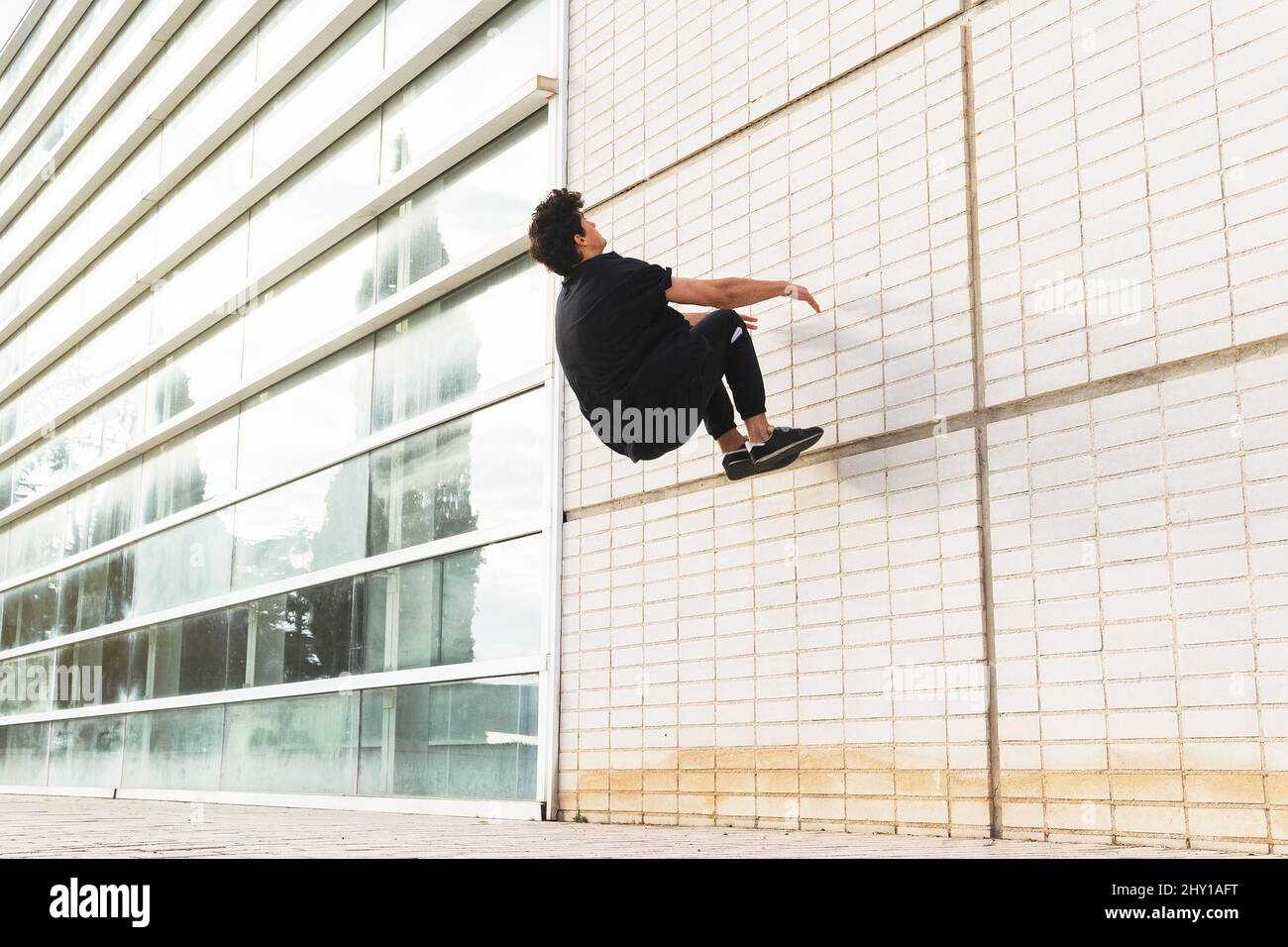 Side view of full length man in black outfit performing acrobatic ...