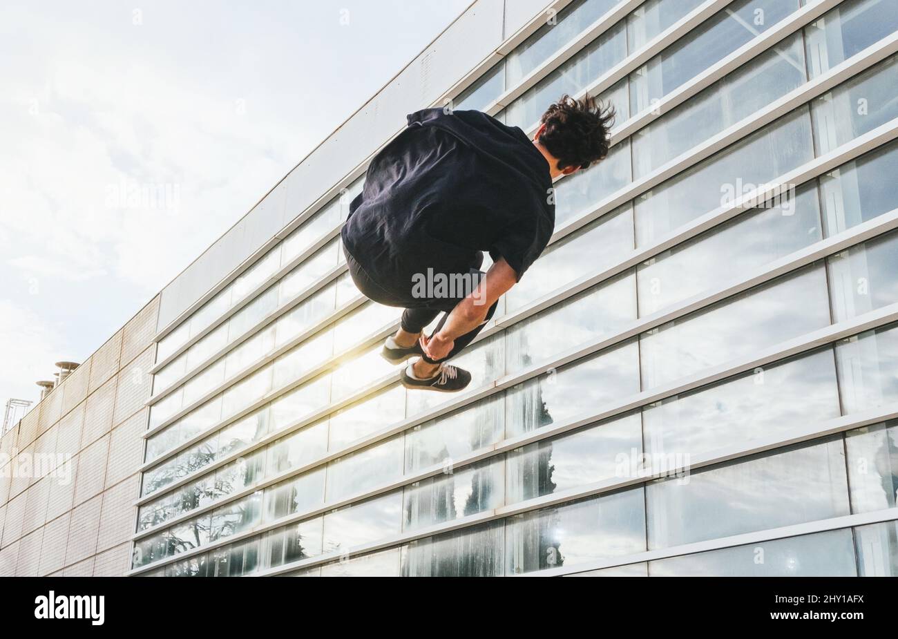 From below back view of anonymous male in casual clothes jumping and ...