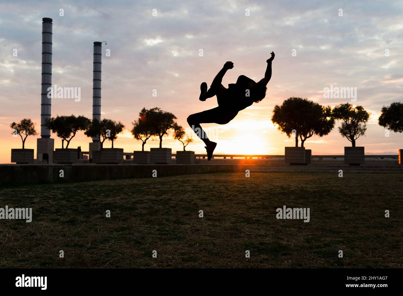 Full body of unrecognizable male silhouette jumping above ground with ...
