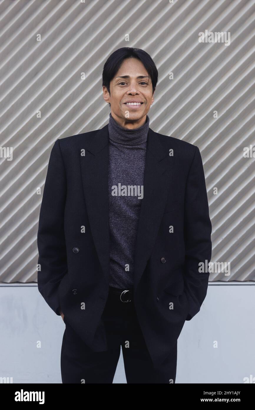 Smiling Indian male with black hair in turtleneck looking at camera ...