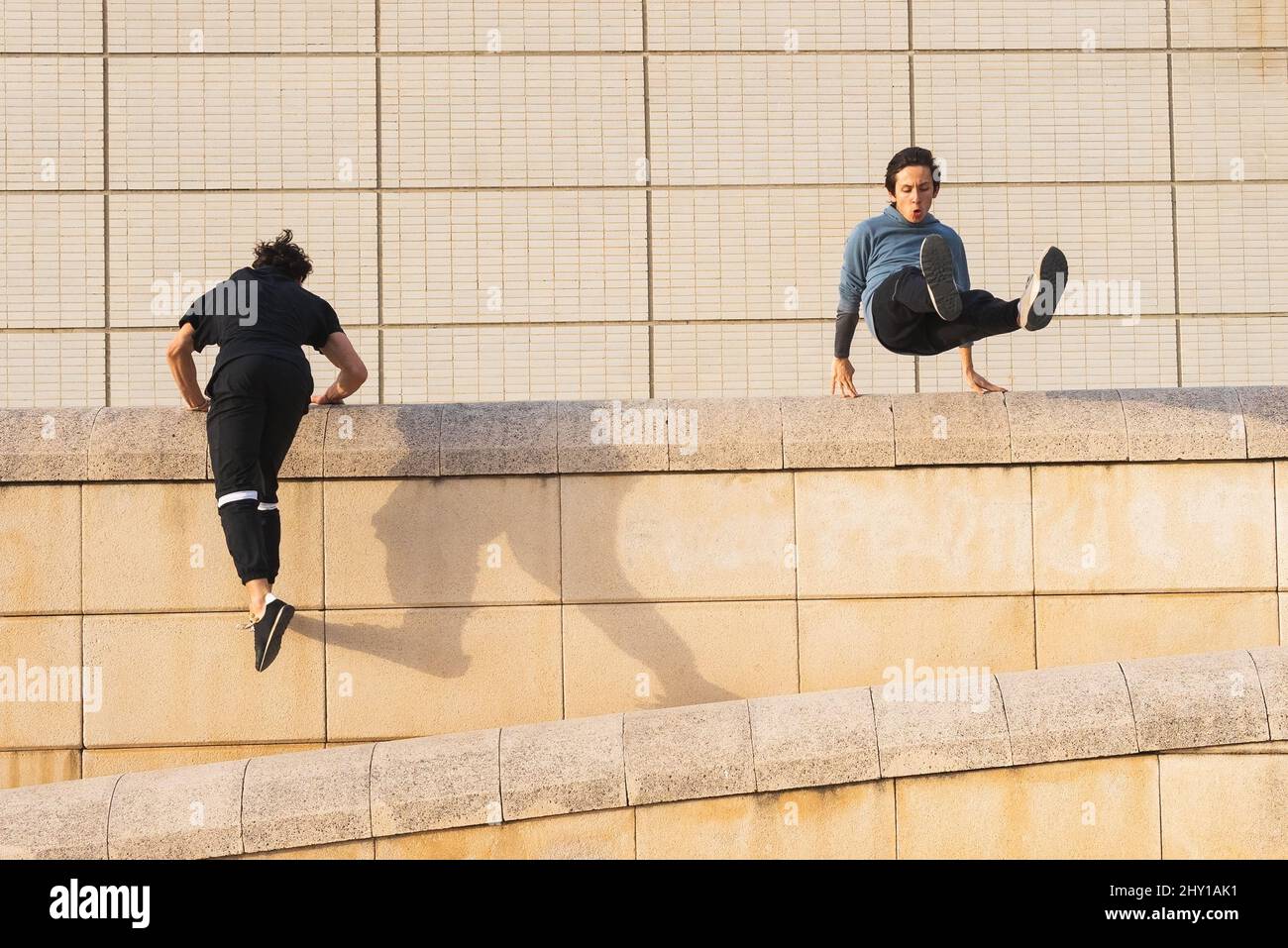 Full body male athletes in sportswear and sneakers parkour jumping ...