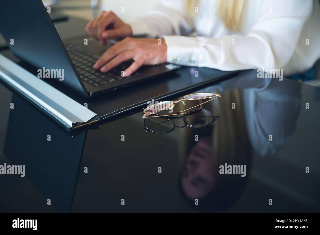 Crop anonymous female employee browsing netbook while working at table ...