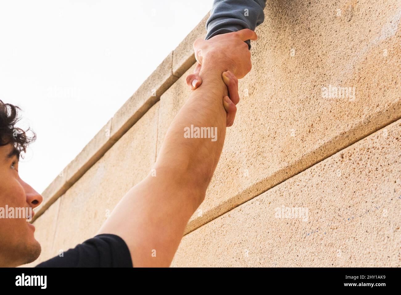 Side view of crop anonymous person in gray clothes on roof holding hand ...