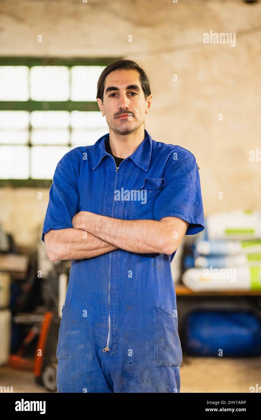 Serious male farmer in uniform looking at camera with arms crossed ...