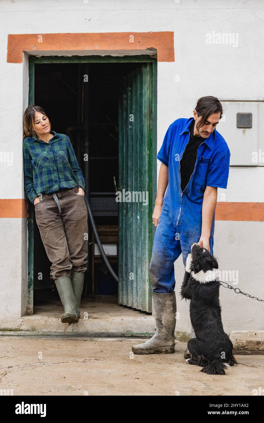 Full body couple of workers in uniforms caressing cute black dog while ...