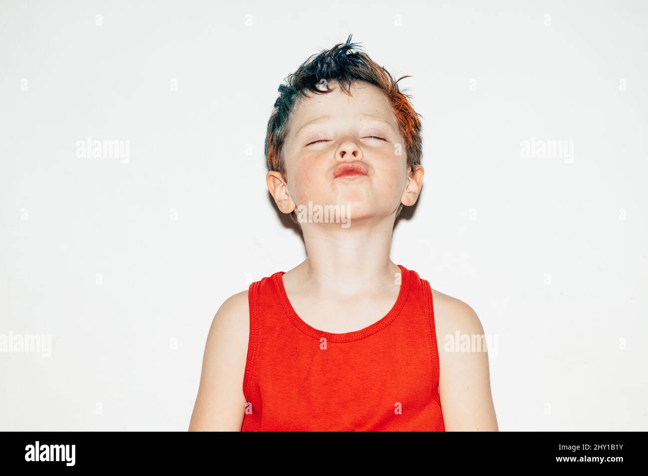 Naughty boy in t shirt with colorful dyed hair pouting lips with closed ...