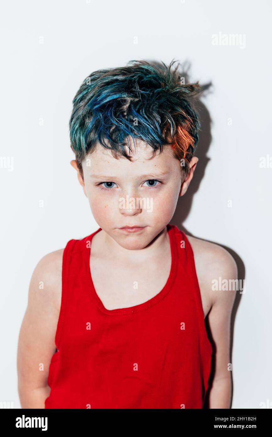 Resentful rebellious boy with dyed hair looking at camera with serious ...