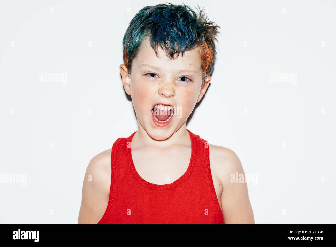 Mischievous boy with colorful dyed hair grinning and showing teeth ...