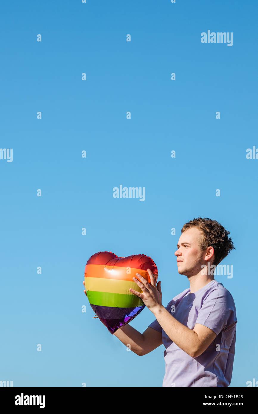 Side view transgender male looking at heart shaped balloon with LGBT ...