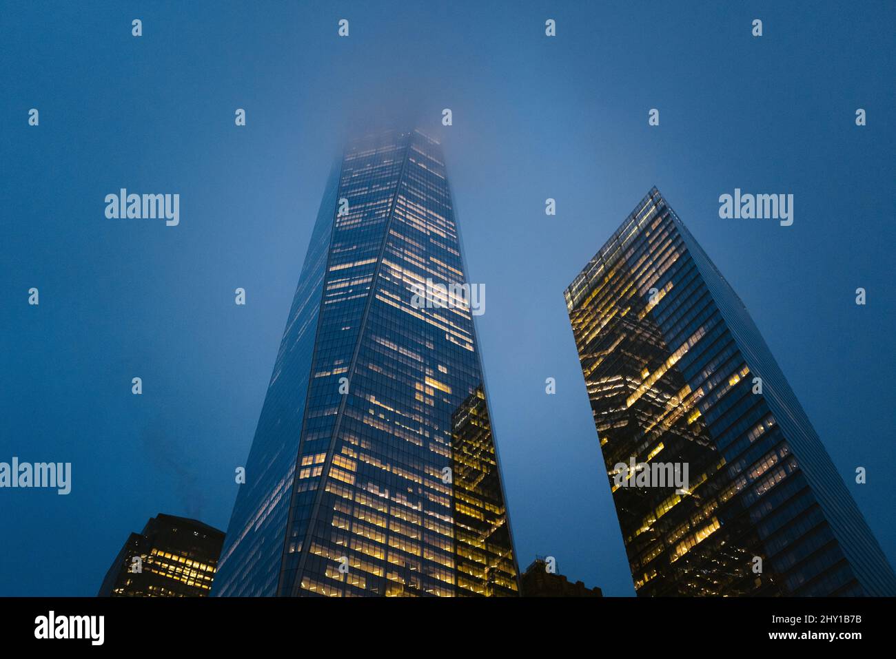 From below of modern high rise buildings with glowing windows located ...