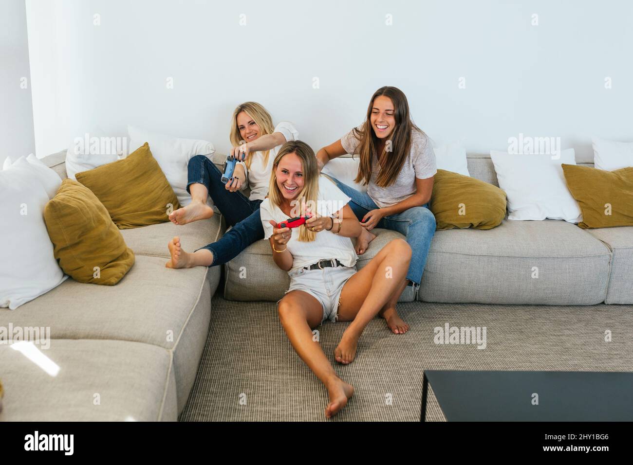 Full body of positive female friends with game controllers playing ...