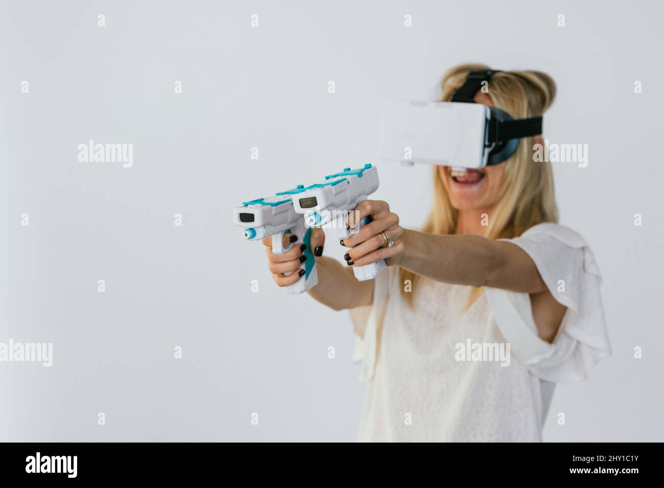 Crop of female in modern VR goggles playing videogame with gamepad with ...
