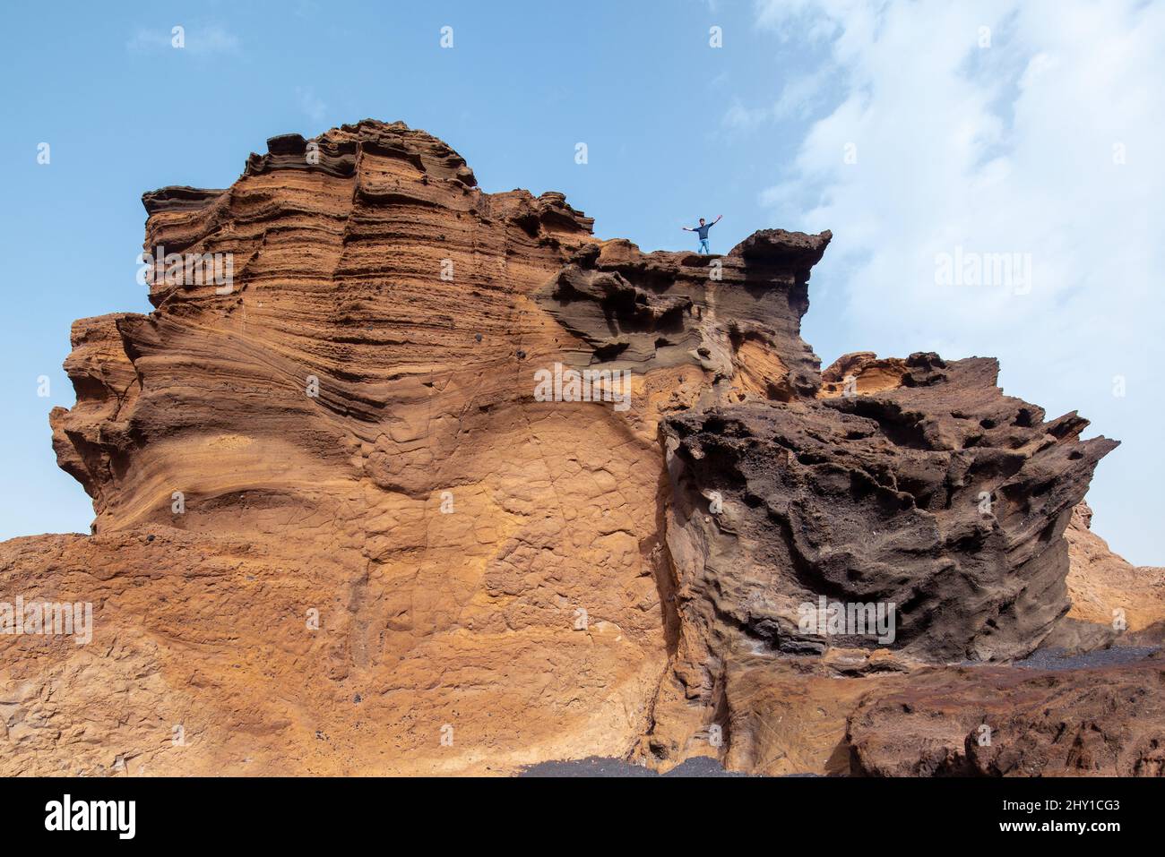 Low angle of traveler enjoying freedom on top of massive rocky cliff ...