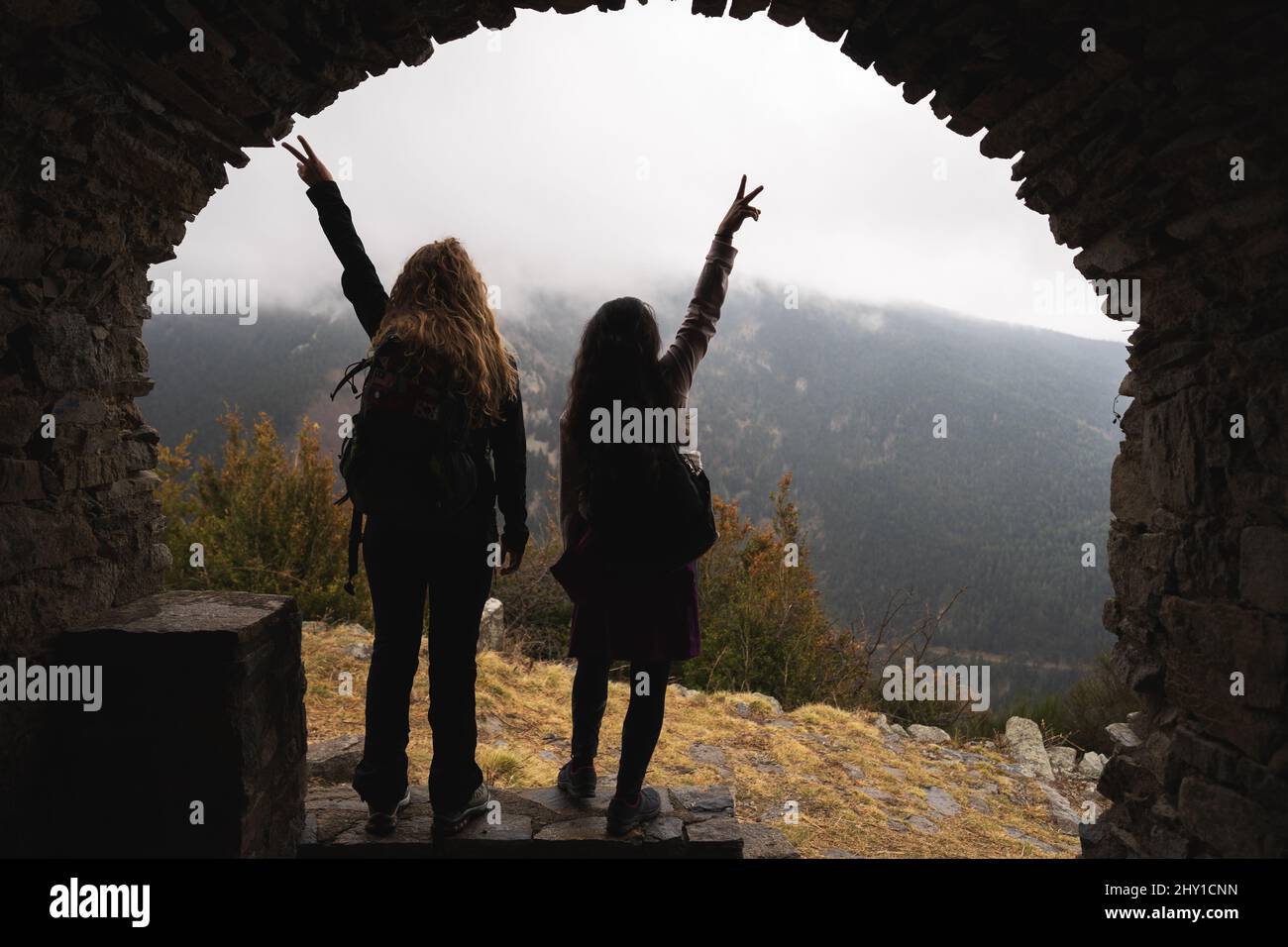 Full body back view of unrecognizable female travelers with raised arms ...