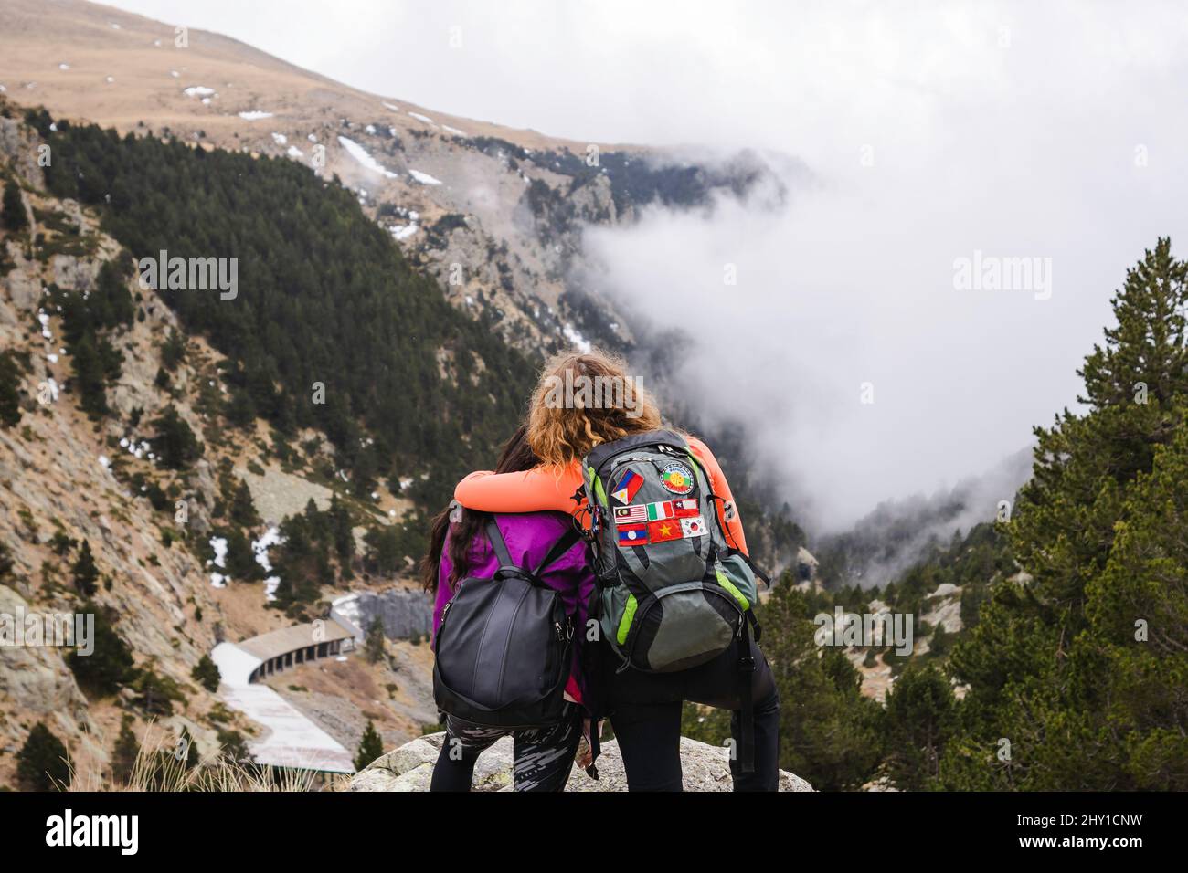 Back view of unrecognizable female travelers with backpacks hugging ...