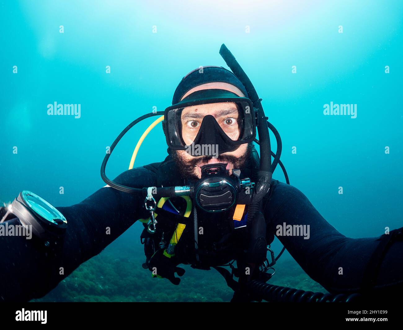 Professional male diver in black wetsuit and snorkeling mask looking at ...