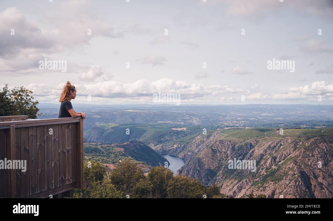 Side view of Woman traveler with curly hair standing on observation ...