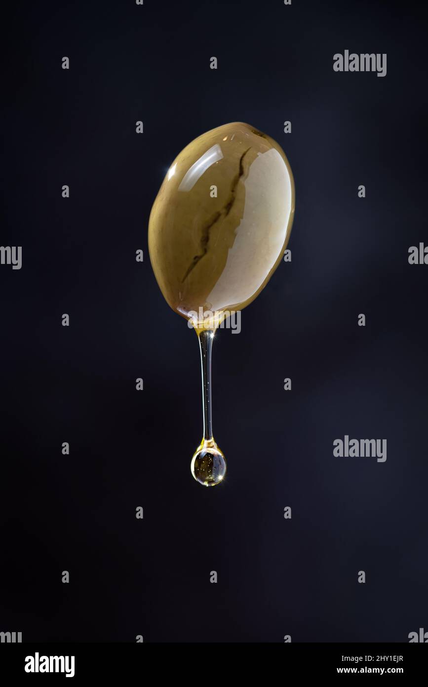 Thin stream of olive oil dripping from square piece of falling dough ...