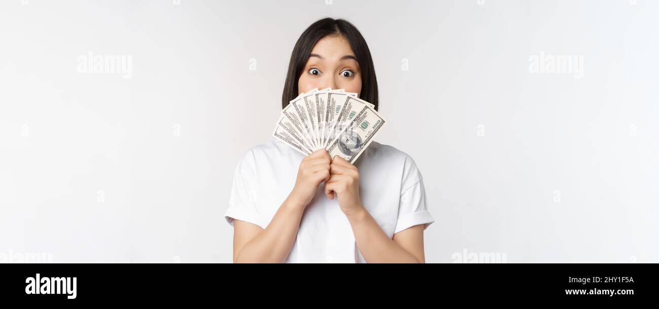 Happy asian girl holding money, cash near face, concept of microcredit ...