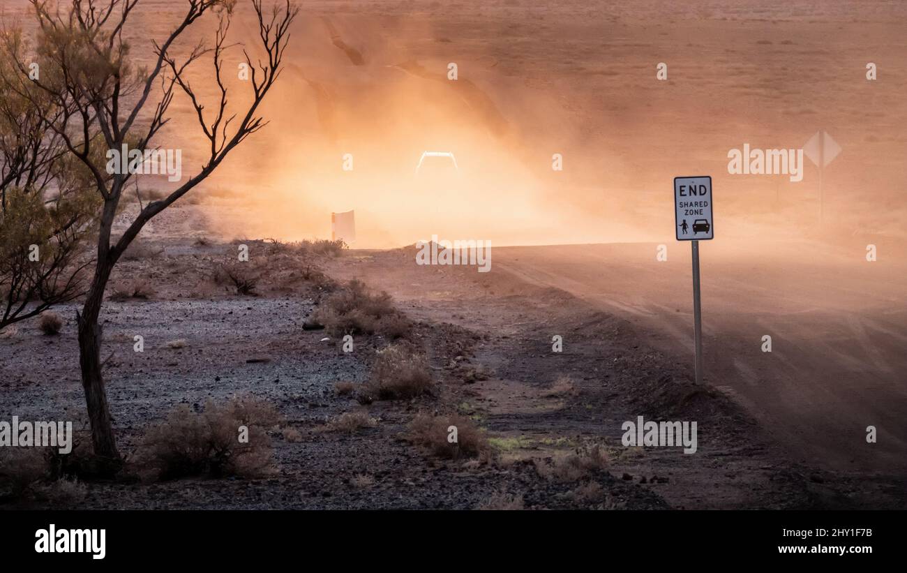 Distant view of a car driving on a dusty unsealed road Stock Photo - Alamy