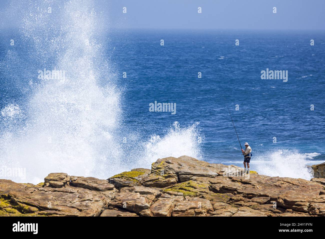 Fisherman on a cliff near Saint Francis Bay with splashing waves in ...