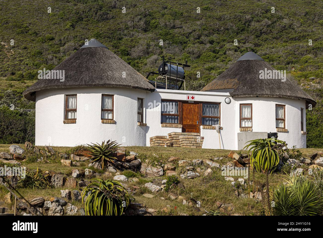 African-style hut (Rondavel) with grey roof and white walls against a ...