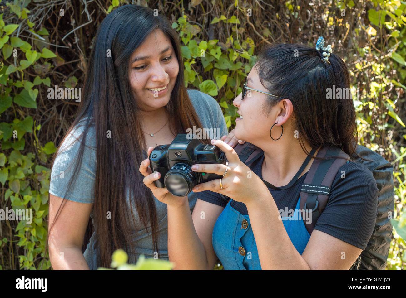 Shot of two girls in a park and having good time together with camera ...