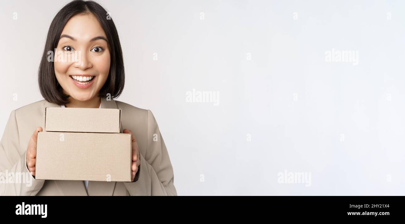 Enthusiastic asian businesswoman, giving customer order boxes, standing ...