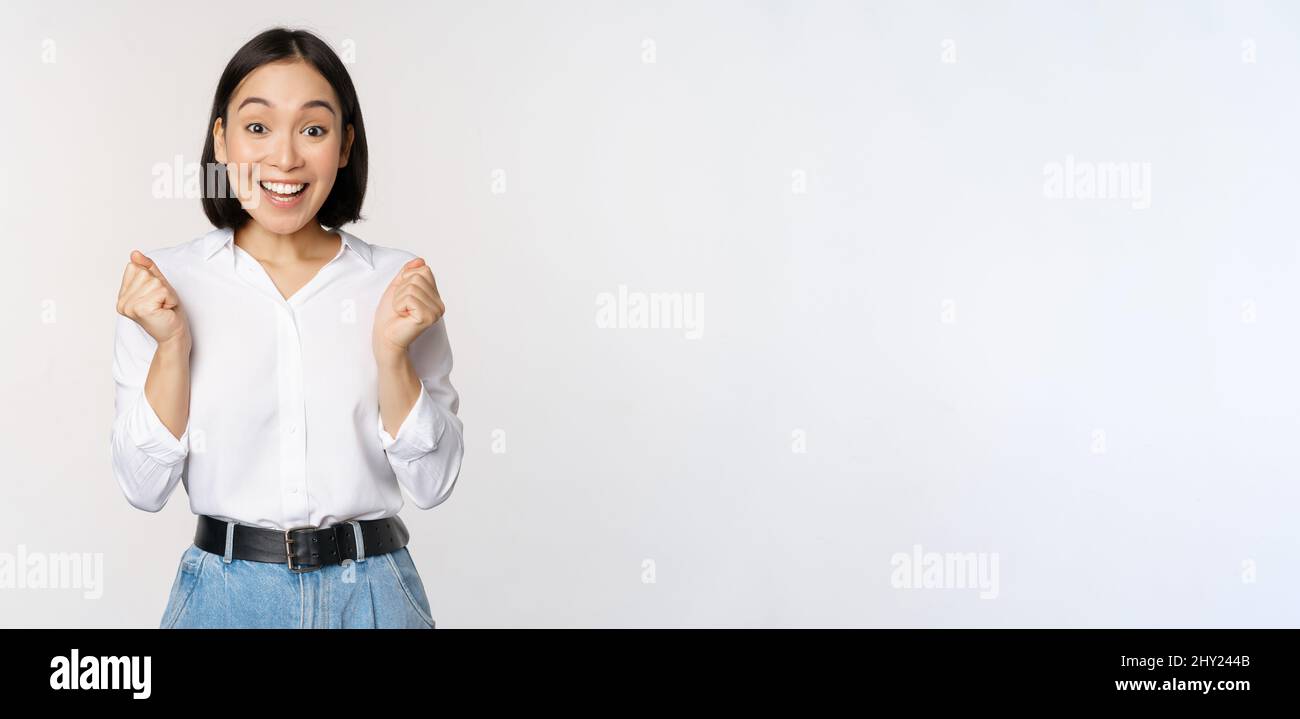 Enthusiastic asian woman rejoicing, say yes, looking happy and ...