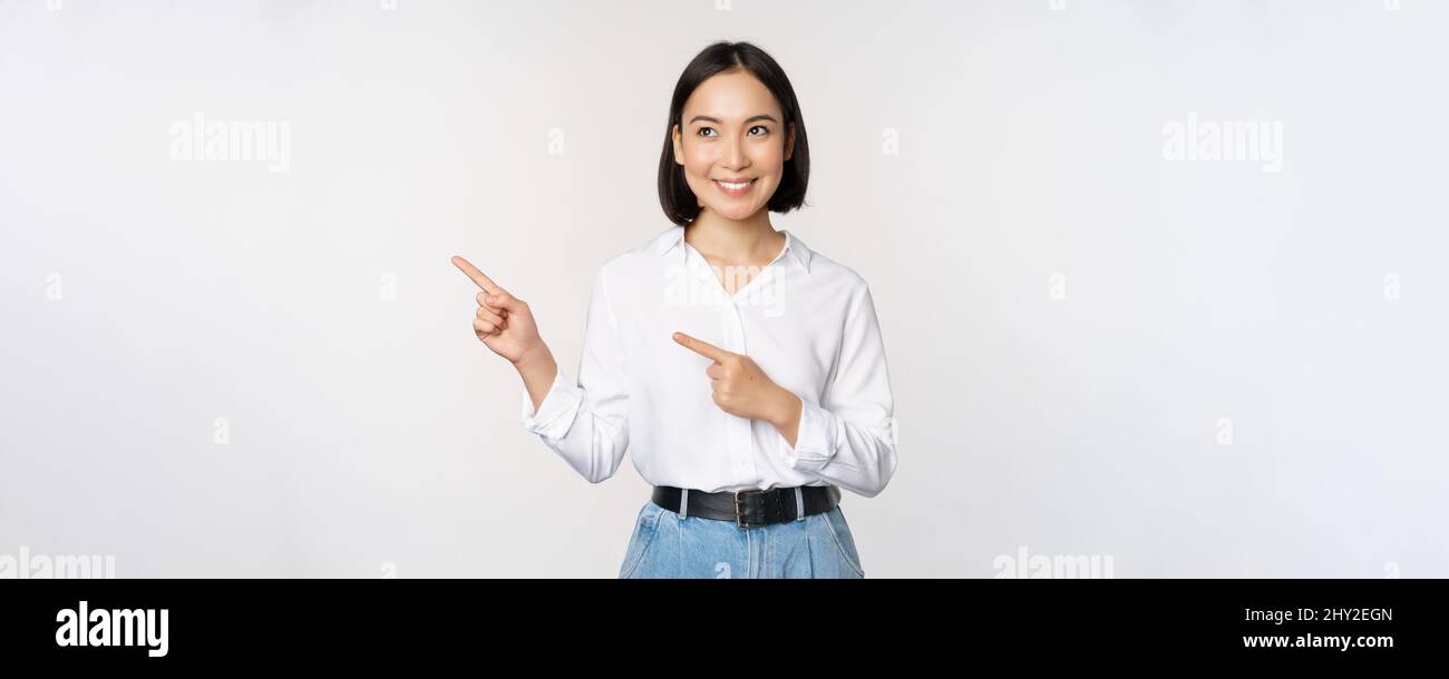 Portrait of attractive adult asian woman pointing, looking left with ...