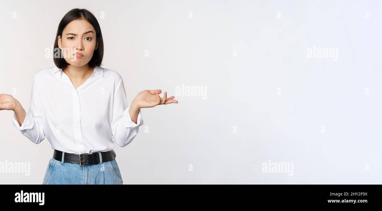 Image of confused asian office manager, office lady shrugging shoulders ...