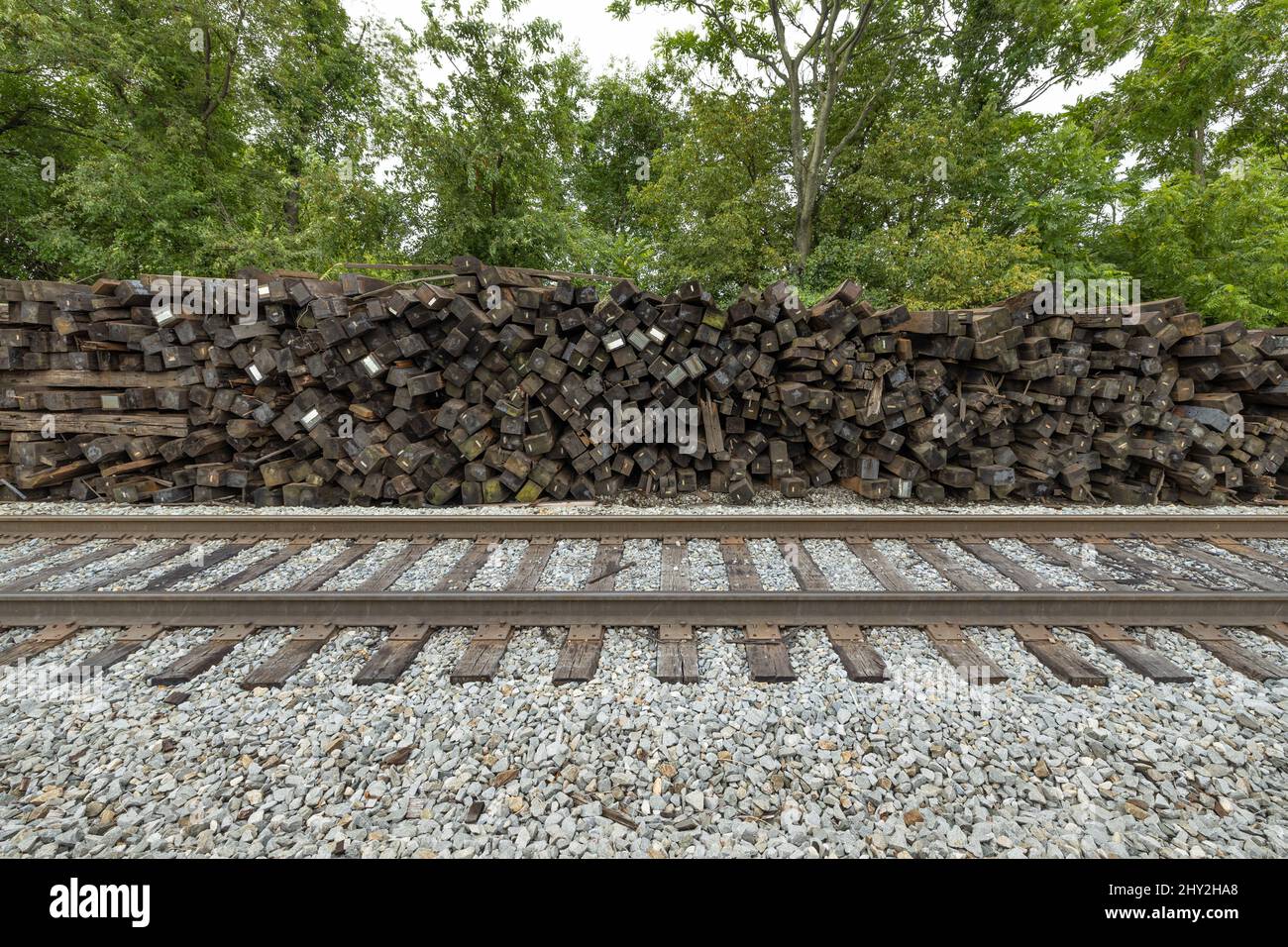 Brown railroad ties piled up next to active train tracks Stock Photo ...