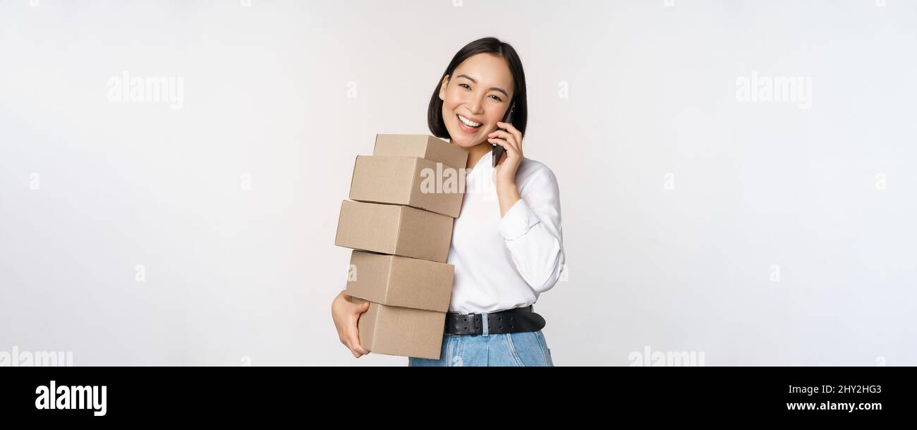 Image of young asian businesswoman answer phone call while carrying ...