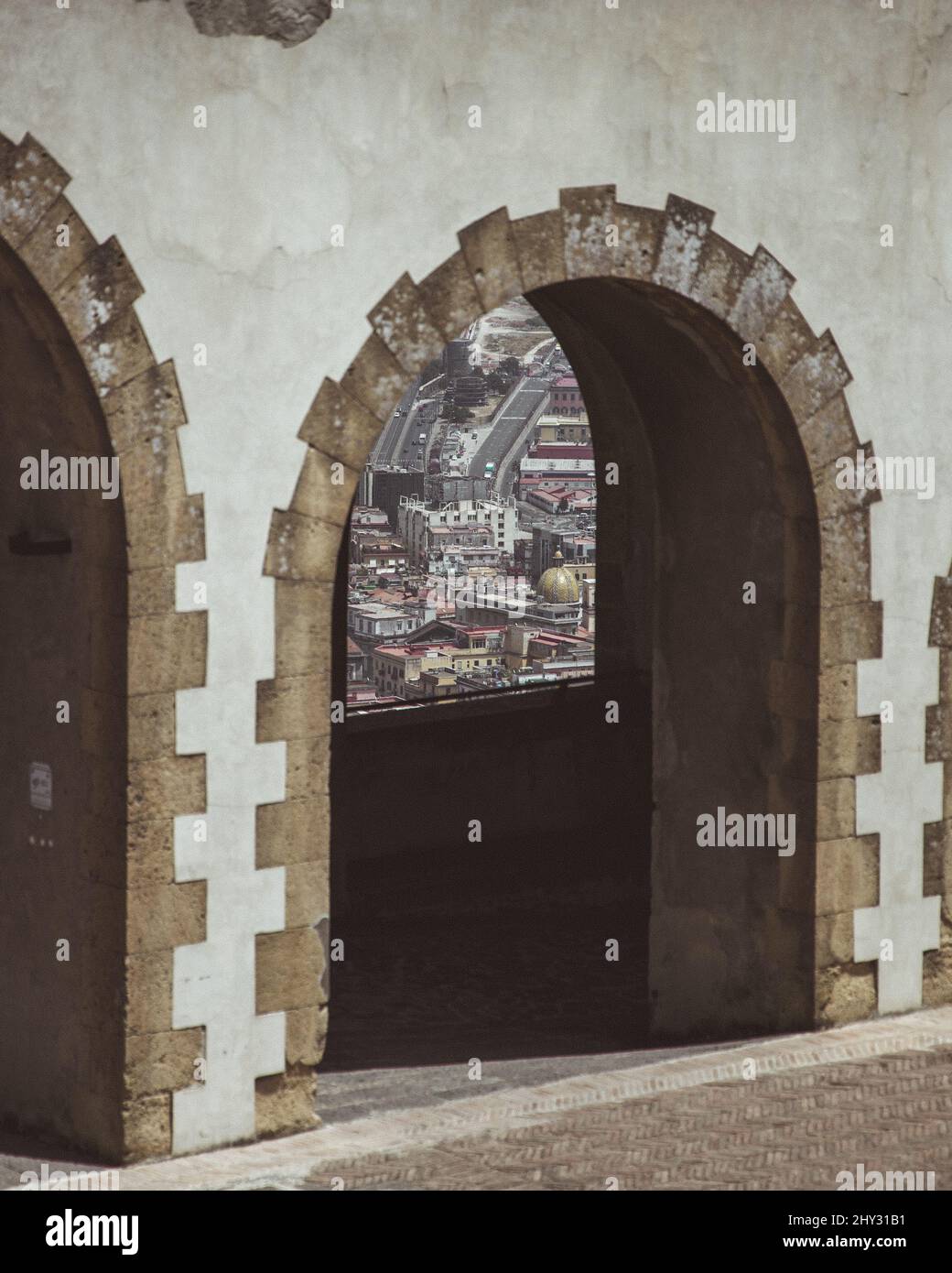 Vertical shot of a medieval arch and a cityscape view inside of it ...