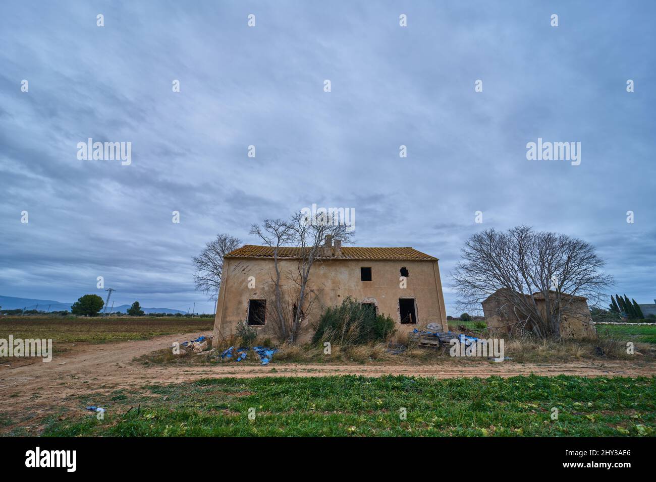 View of a two-storey stone building in the middle of a green field with ...
