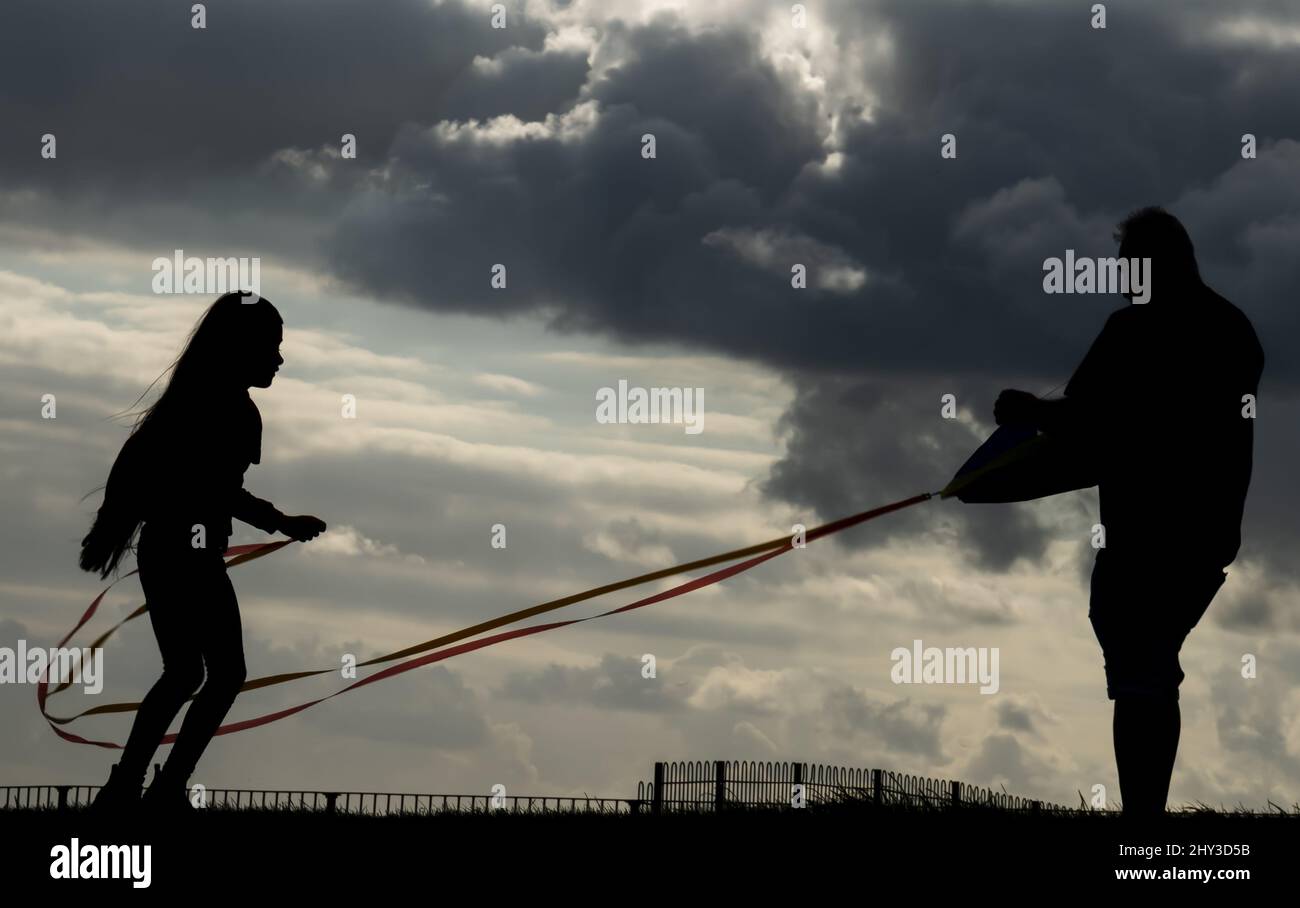 Silloute of kids playing with dark clouds in the background Stock Photo ...