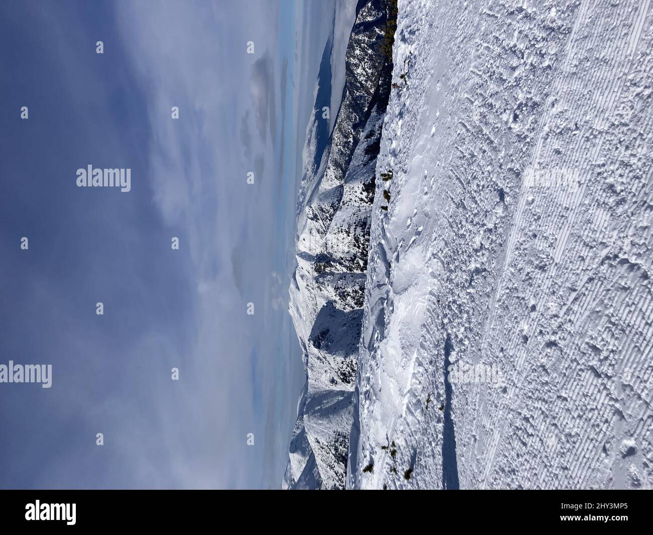 Vertical shot of a mountain range covered with snow under a cloudy sky ...
