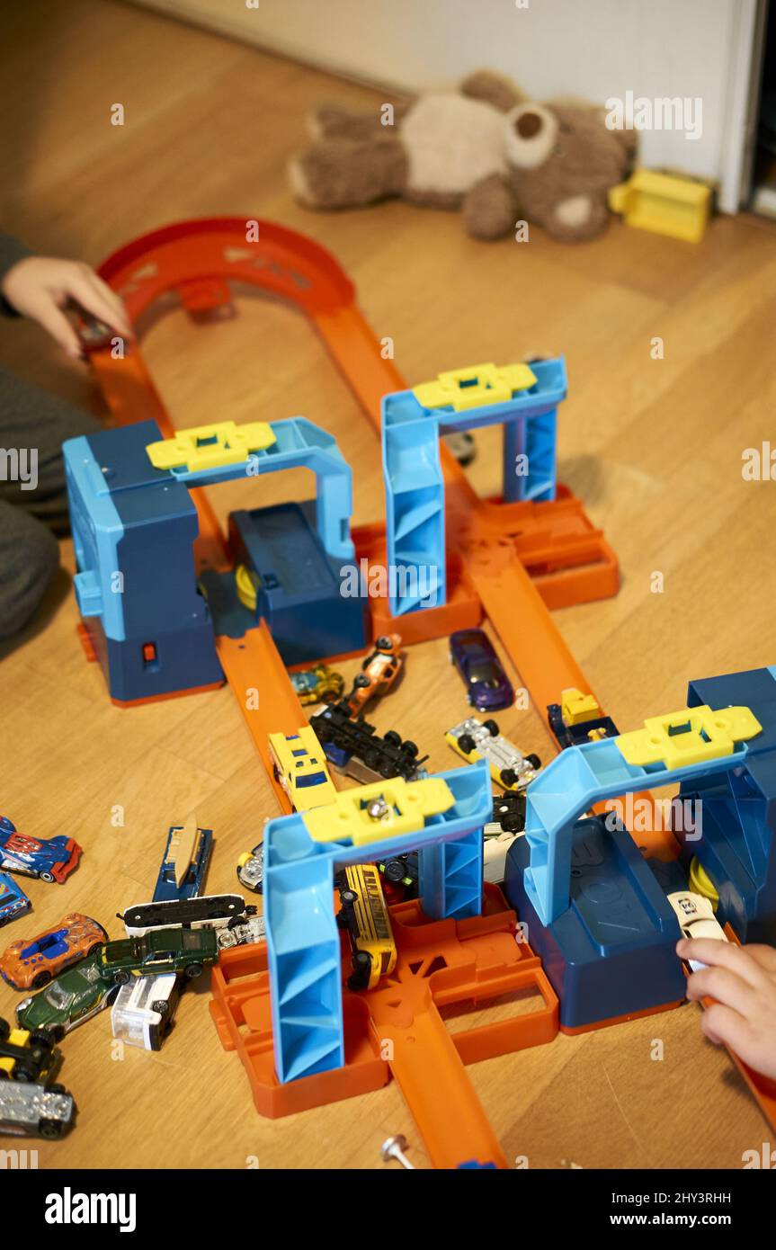 Vertical shot of kids playing with a Mattel Hot Wheels race track in a ...