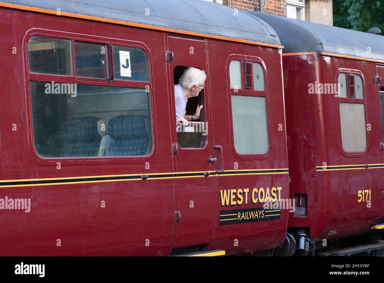 A red train locomotive in Farnborough train station with a man looking ...