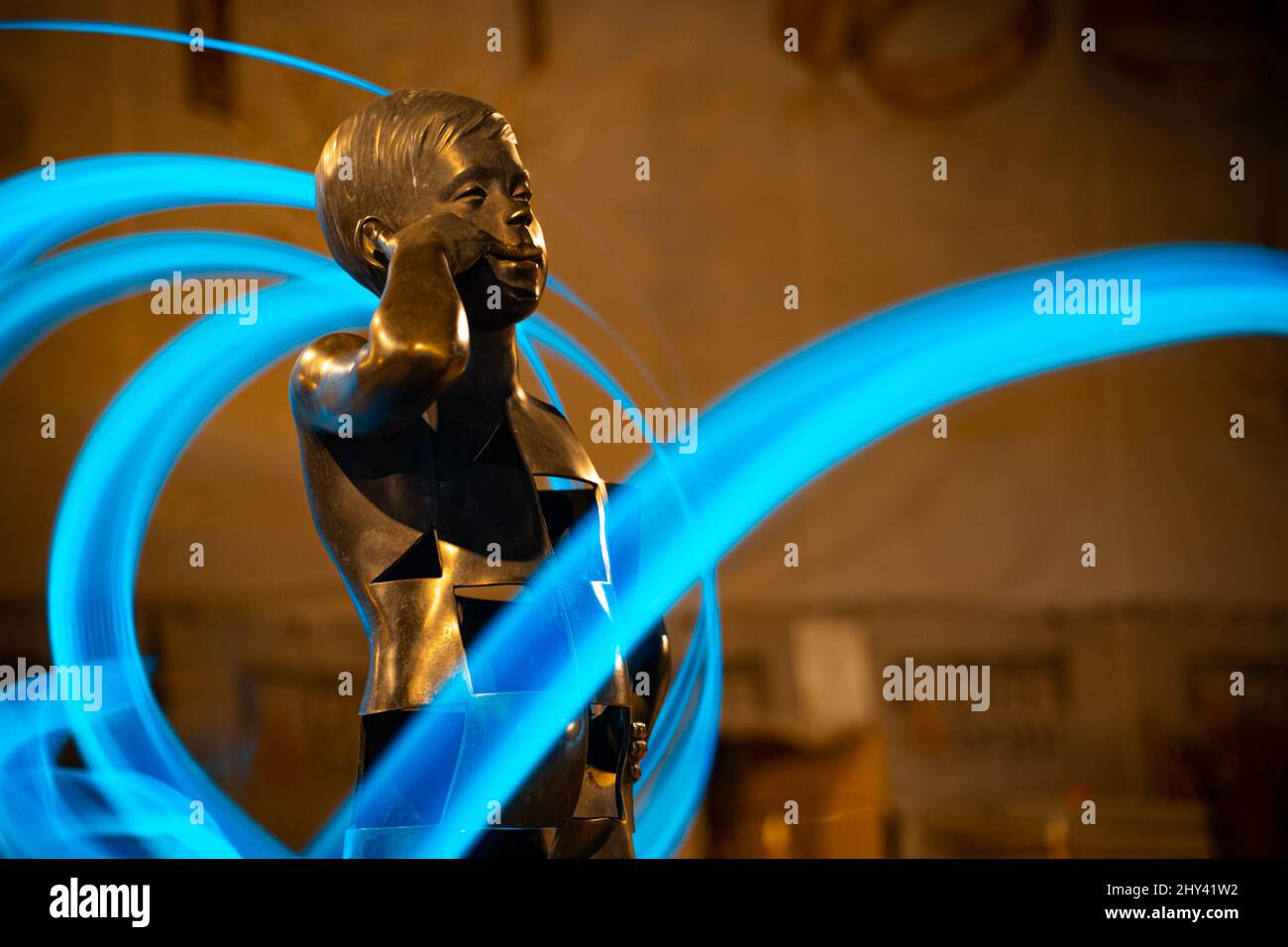 Close-up of a statue of a child and abstract blue neon lights in ...