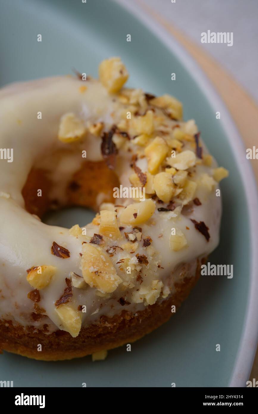 Vertical shot of a glazed donut with crushed nuts as a topping Stock ...