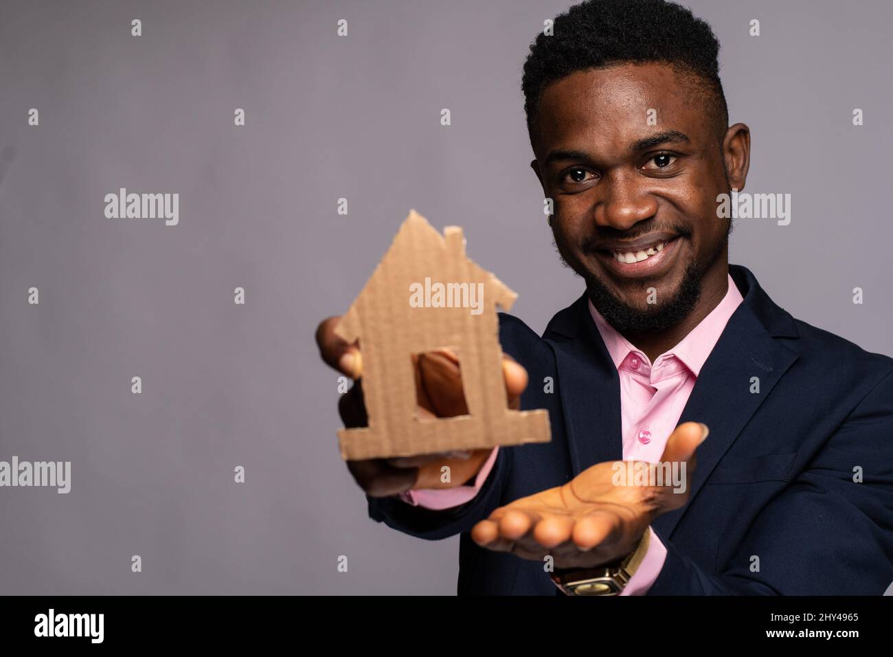 Young African real estate agent showing a cardboard house Stock Photo ...