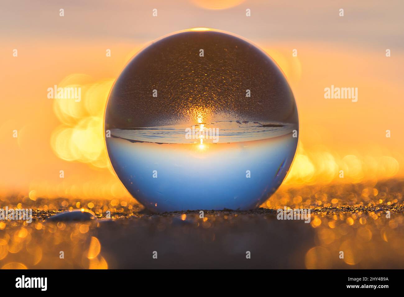 Closeup shot of a clear crystal ball on the beach with the reflection ...
